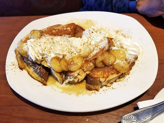 French toast that transcends breakfast into dessert territory, with caramelized bananas and whipped cream playing supporting roles in this morning symphony.