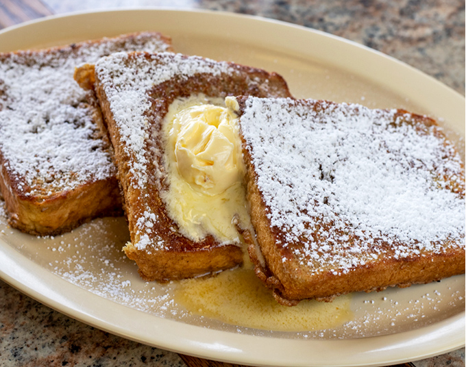 French toast that's achieved the impossible trifecta: crispy edges, custardy center, and enough powdered sugar to make your dentist wince.