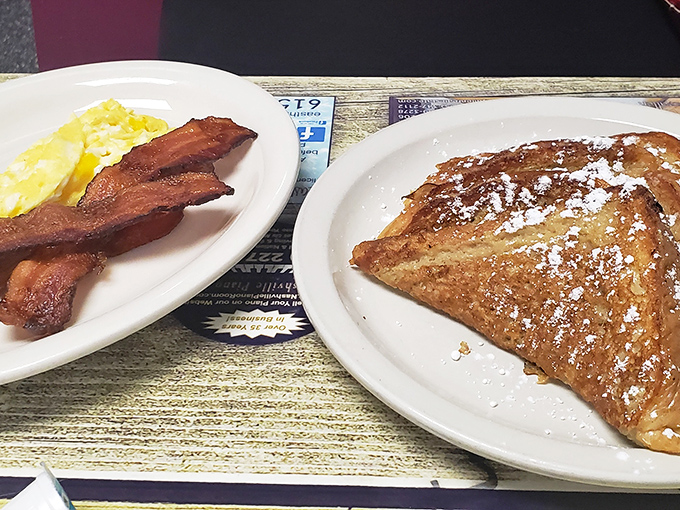 The French toast arrives dusted with powdered sugar, while the bacon stands at attention, ready for its supporting role in breakfast perfection.
