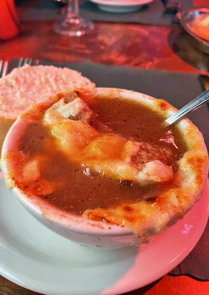 French onion soup that's worth the potential shirt stain – a bubbling cauldron of savory broth beneath a golden cheese canopy.