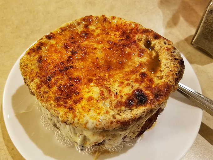 This French onion soup isn't just topped with cheese &ndash; it's wearing a magnificent golden crown that stretches with each spoonful like it's auditioning for a cheese commercial.