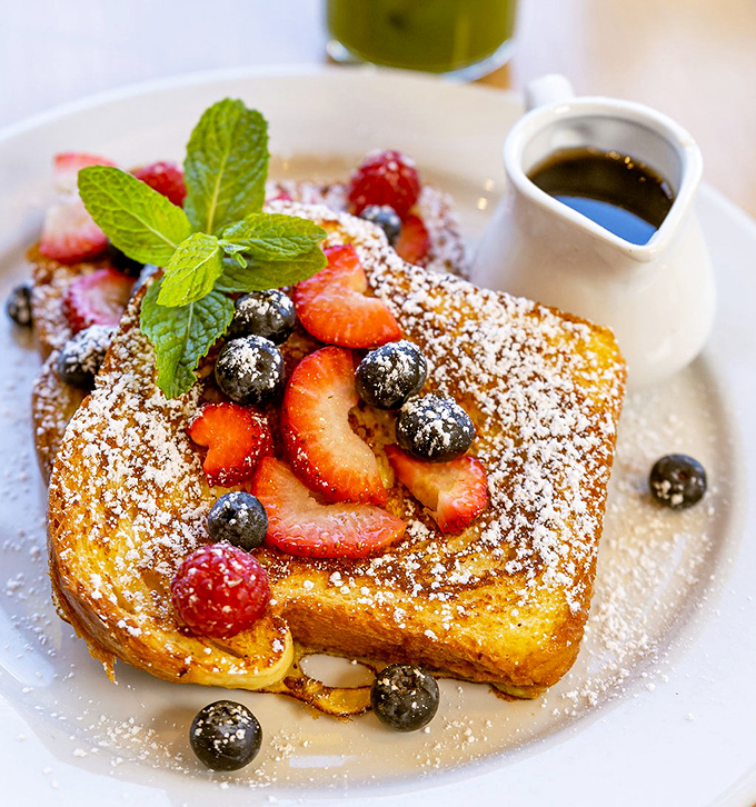 French toast that makes you question every other breakfast you've ever had—golden, custardy perfection crowned with berries and a dusting of powdered sugar.