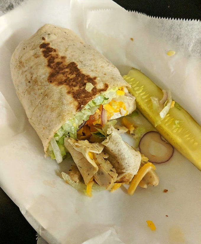 This grilled chicken wrap isn't just lunch; it's a portable masterpiece of flavors, complete with the mandatory pickle spear standing guard like a crunchy sentinel.