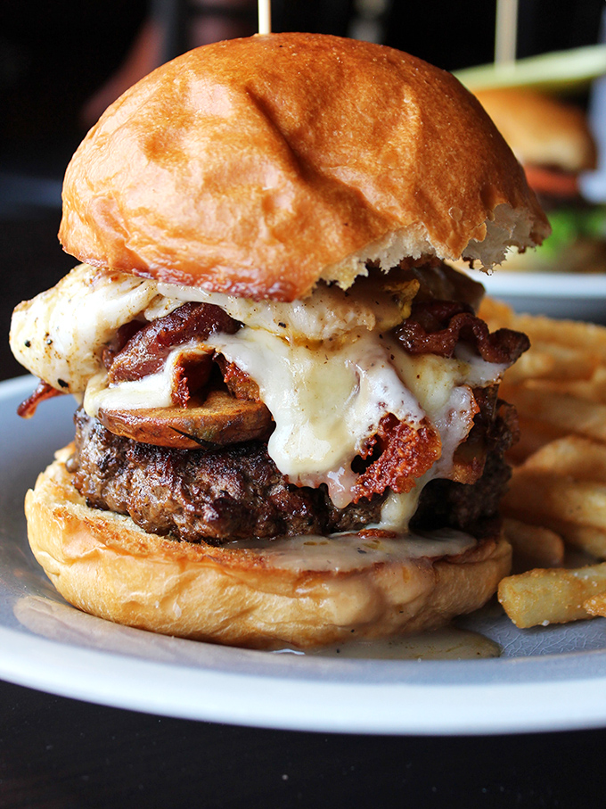 Not just a burger, but a towering monument to indulgence. The melted cheese cascading down the sides is practically begging to be photographed before devoured.