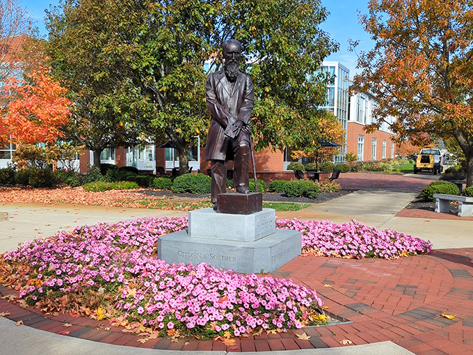 The Henry Solomon Lehr statue stands surrounded by vibrant flowers, a dignified reminder of Ohio Northern University's founder watching over his legacy.