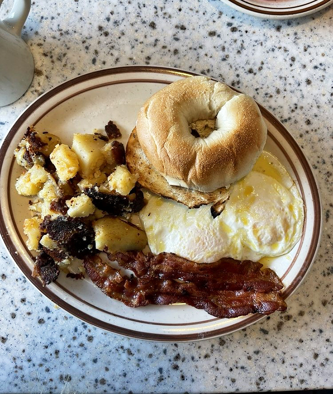 Breakfast perfection on a plate: crispy home fries, perfectly cooked eggs, and a bagel ready for its close-up. Morning glory, diner-style.