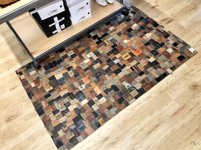 A mosaic of jean tags transformed into functional art. Someone's trash becomes literal floor decor in this creative upcycling masterpiece.