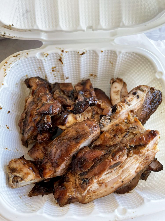 Jerk chicken that looks like it's been kissed by fire and blessed by smoke. Each piece tells a story of patience and skill.