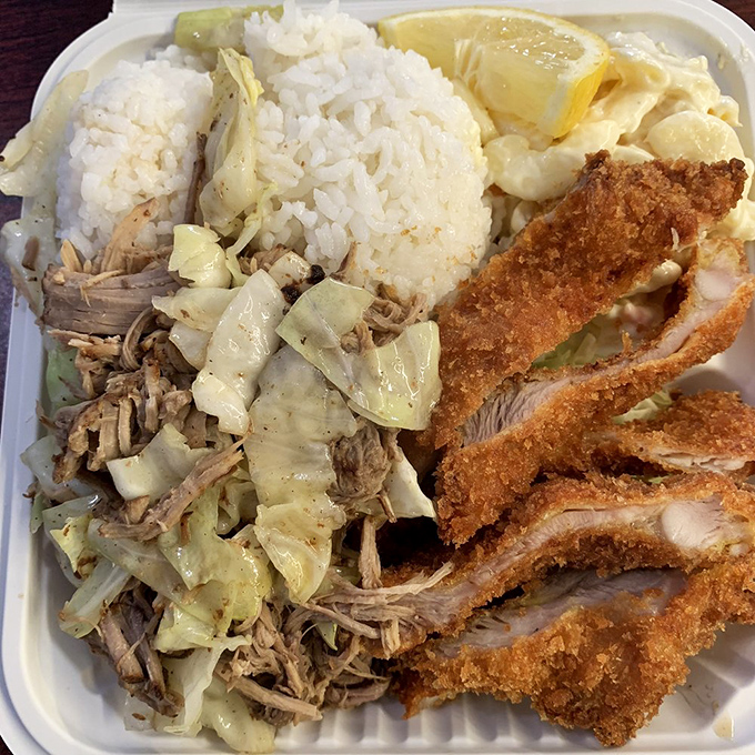 The plate that launched a thousand road trips: kalua pork's smoky tenderness alongside crispy chicken katsu creates harmony in contrasts.