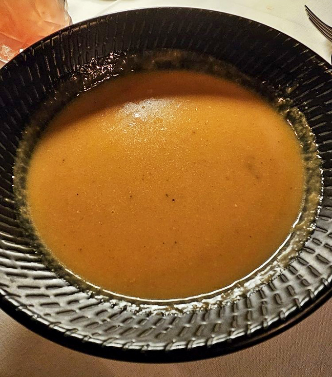 This isn't just soup&mdash;it's liquid gold. The lobster bisque's velvety texture and rich amber color hint at the oceanic treasures within.