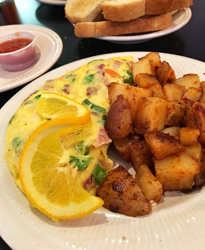 This isn't just any omelet&mdash;it's breakfast alchemy. Ham and veggies folded into fluffy eggs with home fries that could make a potato farmer weep with pride.