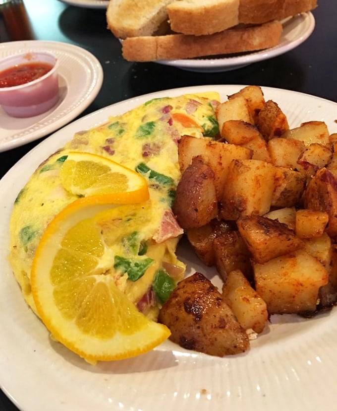 This isn't just an omelet—it's breakfast architecture. Golden eggs folded around ham and veggies with home fries that deserve their own zip code.