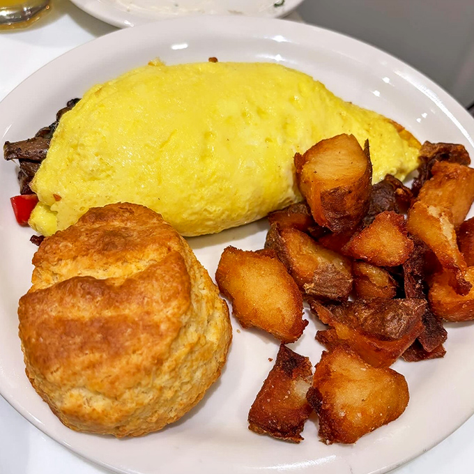 This isn't just an omelet; it's a golden-hued sunrise on a plate, complete with home fries that could make a potato proud.
