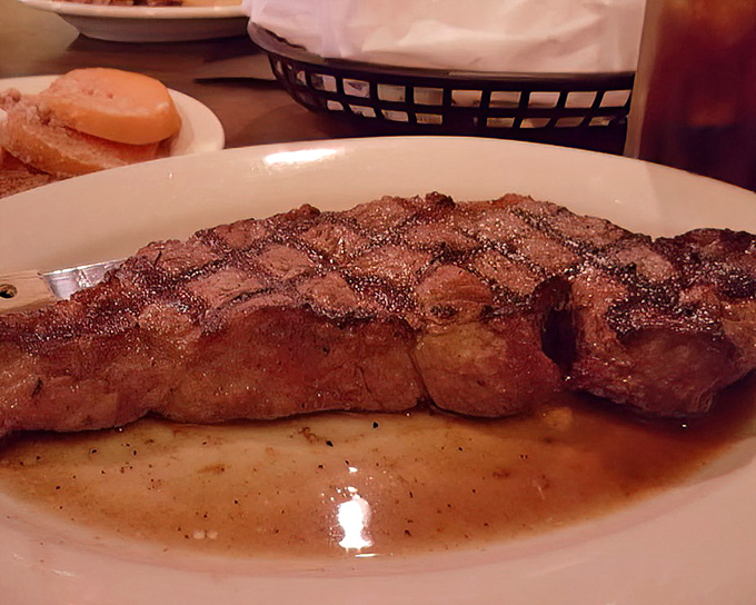 A New York Strip with the perfect crosshatch grill marks sitting in its own juices. This isn't just a steak &ndash; it's a masterclass in meat preparation.