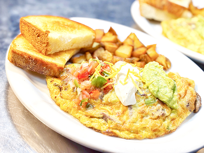 This isn't just an omelet; it's a fluffy yellow canvas painted with fresh vegetables and topped with the holy trinity: sour cream, pico, and avocado.