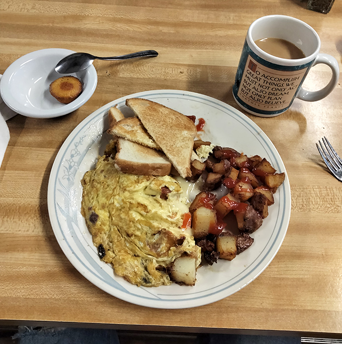 A perfect breakfast trinity: fluffy omelet, crispy home fries, and toast done right. Simple pleasures executed with diner precision and care.