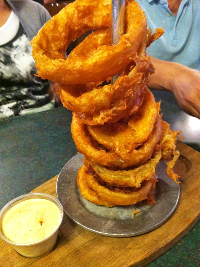 Onion rings stacked like golden Olympic rings&mdash;crispy, light, and the perfect vehicle for that creamy dipping sauce waiting patiently on the side.
