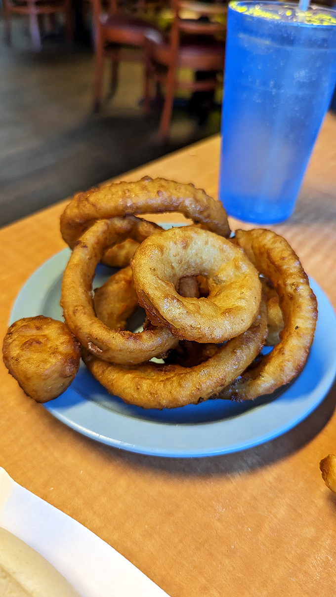 Golden, crispy onion rings that shatter with each bite, paired with an electric blue drink. Americana on a plate.