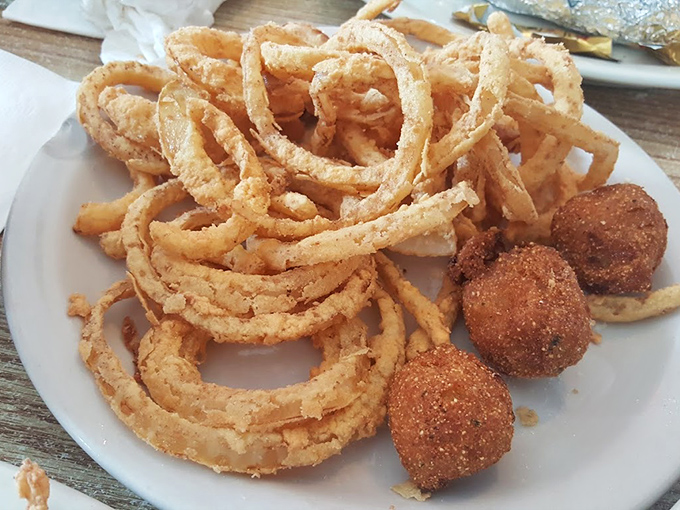 Onion rings and hush puppies sharing a plate like old friends&mdash;crispy, golden companions that make you wonder why vegetables ever bothered growing any other way.