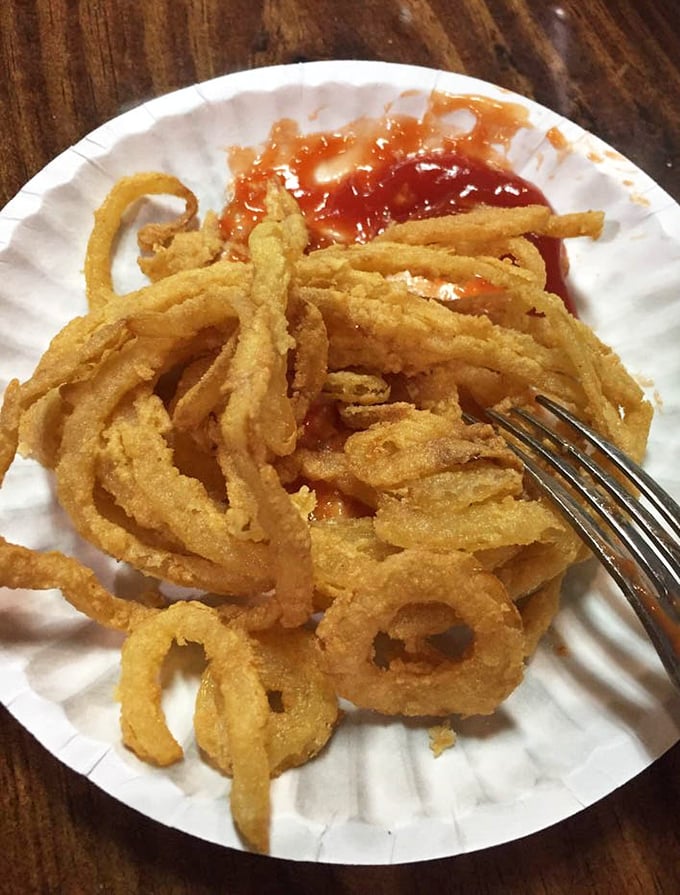 These aren't just onion rings; they're golden halos of happiness that somehow manage to maintain their structural integrity with every blissful bite.