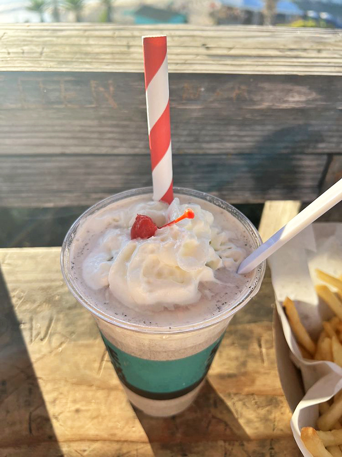 Not just a milkshake but a work of art—candy-striped straw, cloud of whipped cream, and that perfect blue hue that matches the ocean view.