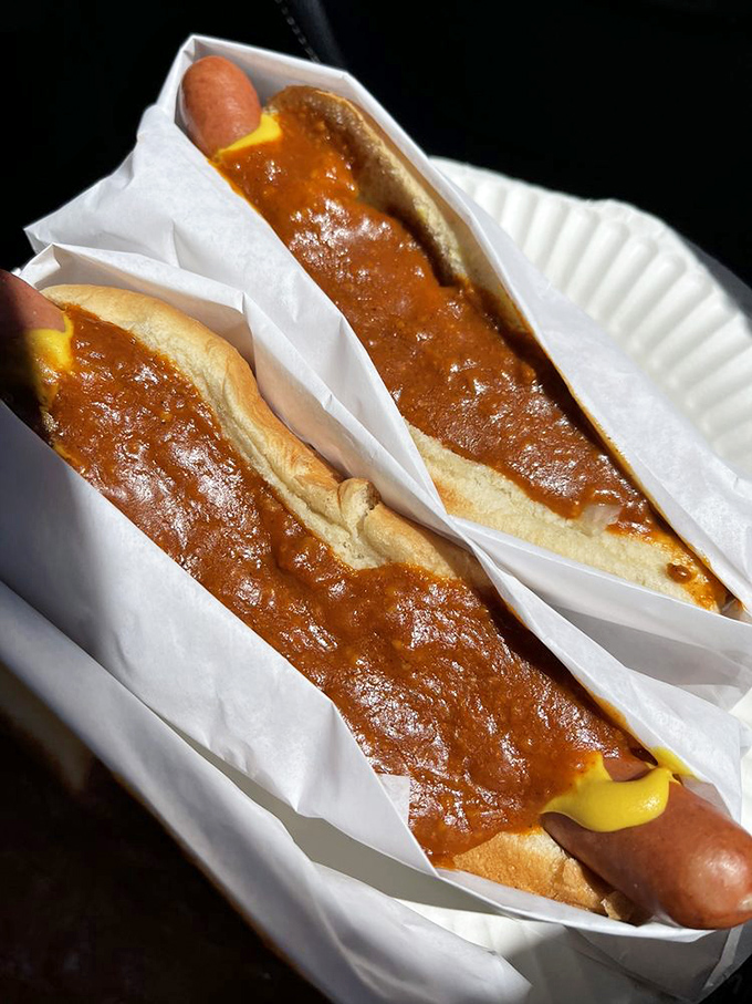 Chili dogs bathed in sunshine and possibility. The mustard zigzag isn't just condiment art&mdash;it's a yellow brick road to flavor town.