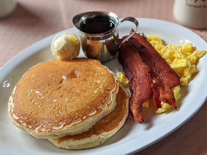 The pancake trinity: golden discs, crispy bacon, and fluffy eggs. Breakfast perfection that would make your grandmother both proud and jealous.
