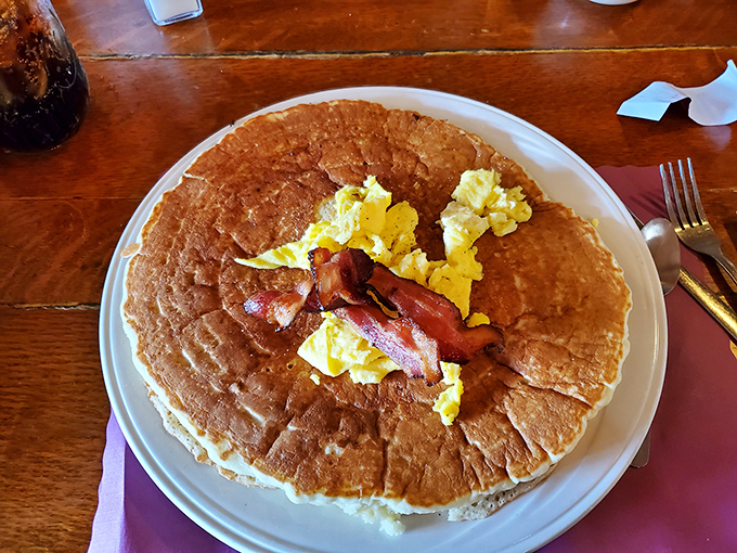 Pancakes so vast they need their own zip code. The bacon and eggs look like they're floating on a golden breakfast raft.