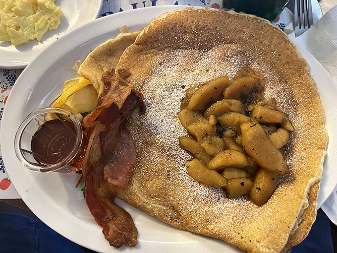 The legendary Danish pancake in its natural habitat, crowned with caramelized apples and accompanied by what might be the world's most necessary side of bacon.