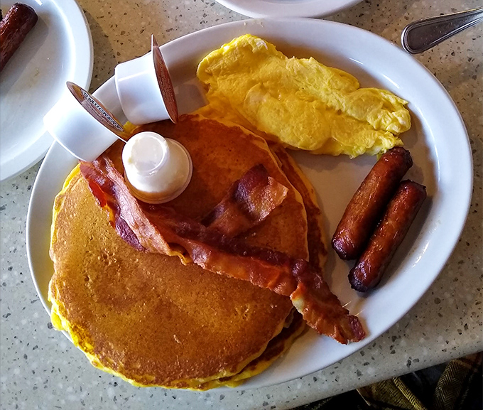 Pancakes, bacon, and eggs &ndash; the holy trinity of breakfast foods arranged on a plate like old friends at a reunion.