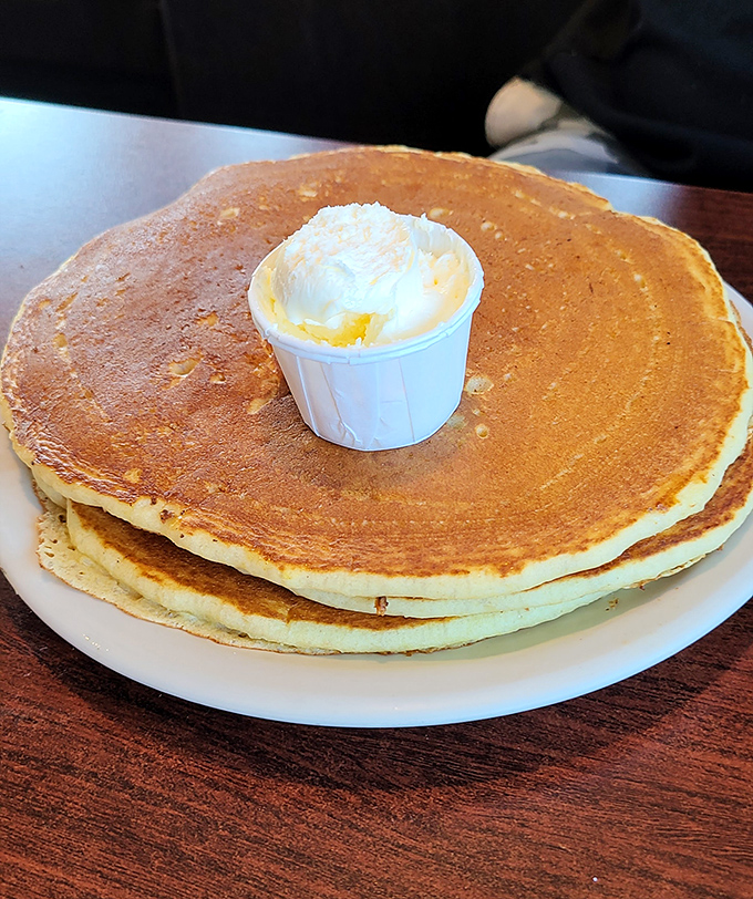Pancakes so perfectly golden they deserve their own spotlight, with a dollop of butter melting like a headliner taking center stage.
