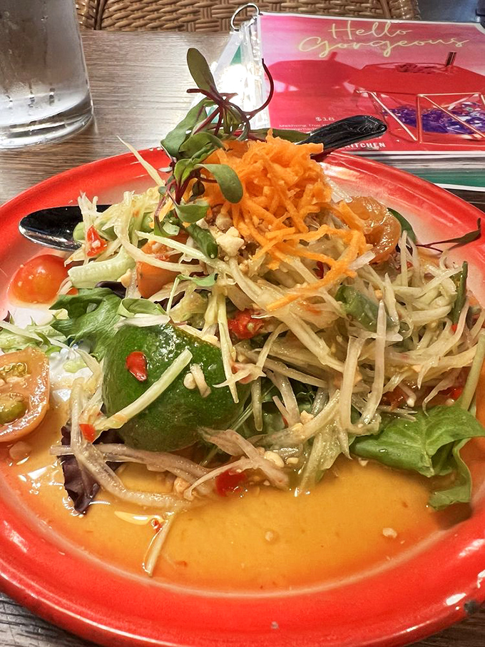The papaya salad arrives like a vibrant celebration, with each bite delivering that perfect Thai harmony of sweet, sour, salty, and spicy that makes your taste buds dance.