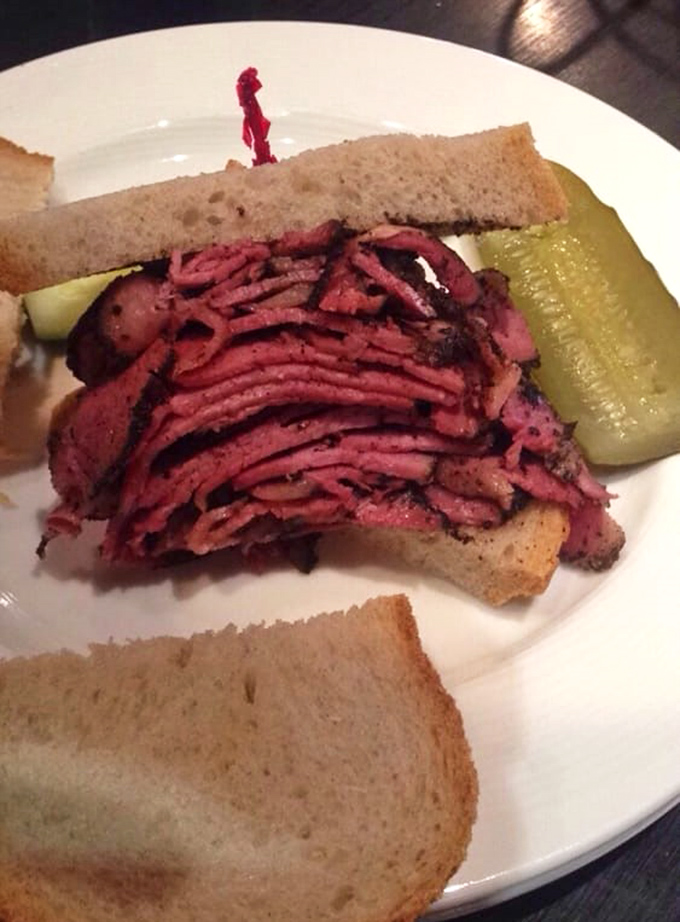 This isn't just a pastrami sandwich; it's an architectural marvel of thinly-sliced, perfectly-spiced meat that demands both your respect and your appetite.