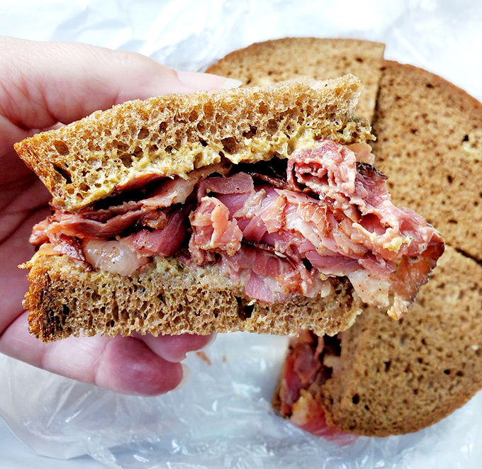 Pastrami piled so high it needs its own zip code. The rye bread is merely trying to contain what can only be described as meat magnificence.