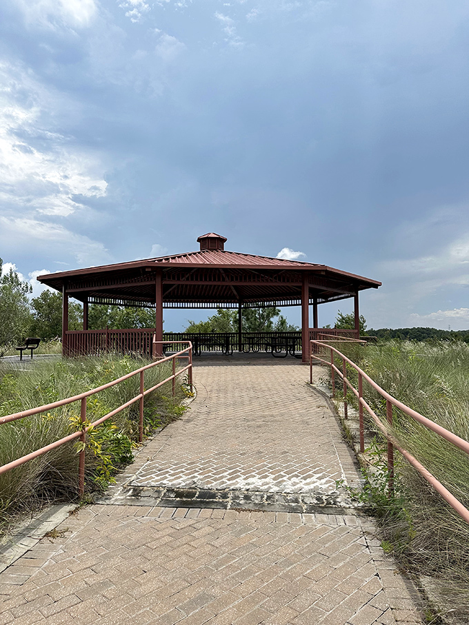 The lakeside gazebo stands like a contemplative philosopher overlooking the water, offering shade and perspective in equal measure.