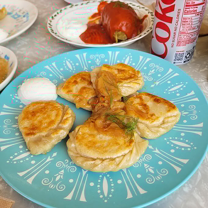 Golden-brown pierogi lounging on a turquoise plate&mdash;each one a perfect pocket of potato pleasure waiting to change your life.