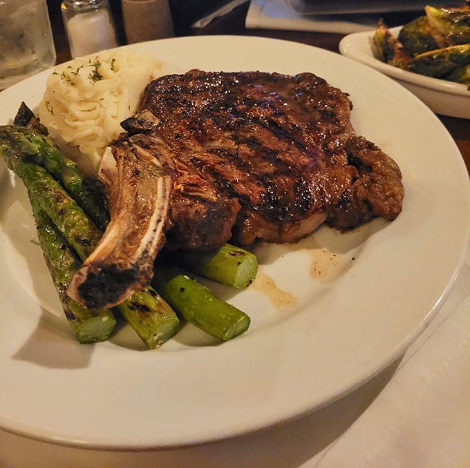This bone-in ribeye isn't just a steak; it's a monument to carnivorous pleasure, complete with grill marks that belong in an art gallery. 
