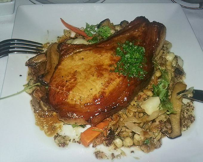 This pork chop isn't just dinner; it's a masterclass in caramelization, perched atop a garden of vegetables like a king surveying his delicious domain.