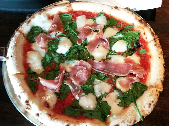 Prosciutto and fresh basil play hide-and-seek with pools of melted mozzarella on this Neapolitan masterpiece.