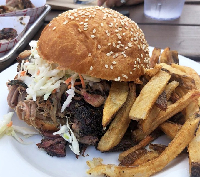 This isn't just a sandwich; it's an architectural marvel of smoke-kissed pork, crunchy slaw, and a bun that somehow maintains structural integrity against impossible odds.