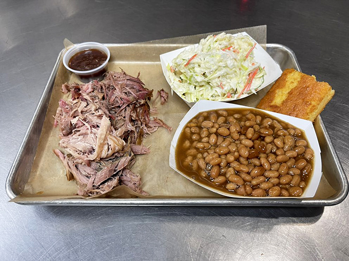 Pulled pork in its natural habitat &ndash; tender, smoky strands alongside creamy slaw, baked beans, and cornbread that demands attention.