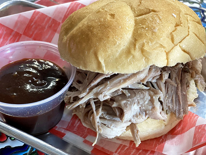 A pulled pork sandwich so tender it practically surrenders to gravity, served with a side of barbecue diplomacy.