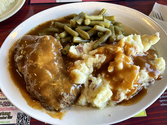 Salisbury steak swimming in rich gravy alongside cloud-like mashed potatoes and green beans – the kind of plate that makes you want to call your mother.