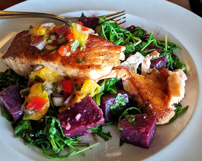 Pan-seared salmon nestled atop vibrant baby greens proves that healthy eating never tasted this indulgent.
