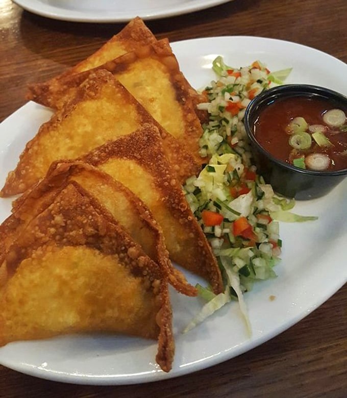 Crispy wontons filled with savory goodness arrive like edible envelopes containing delicious secrets, accompanied by a fresh veggie slaw.