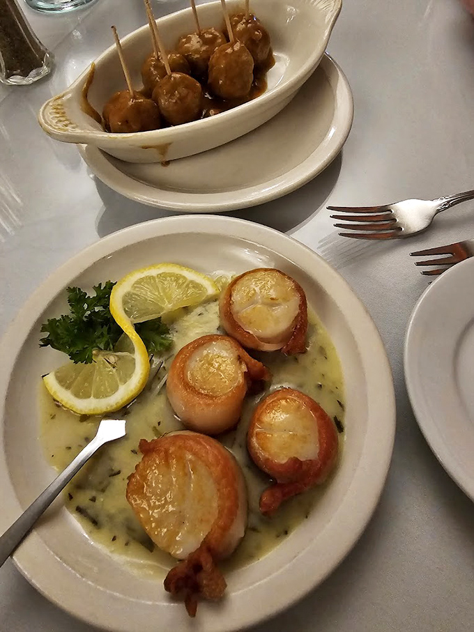 These bacon-wrapped scallops swimming in herb butter aren't just appetizers—they're little ocean-kissed pillows that make you temporarily forget about the prime rib to come.