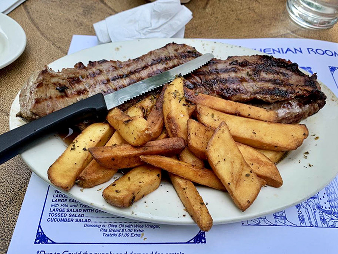 The skirt steak arrives like a meaty masterpiece atop those legendary Greek fries, which soak up the juices like flavor-hungry sponges.