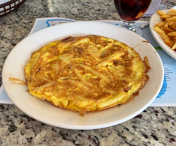 The Spanish omelet sits golden and proud, thick as a phone book from the days when we had phone books.