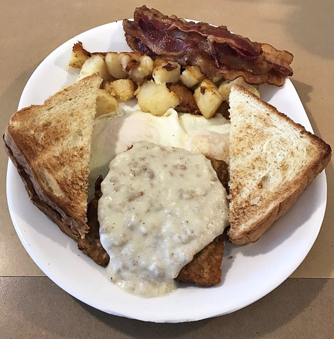 Breakfast perfection on a plate: country-fried steak smothered in gravy, eggs, home fries, and toast. The breakfast of champions who plan to nap afterward.