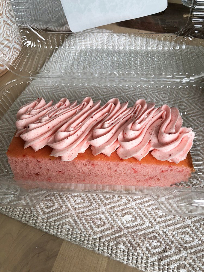 This strawberry slice isn't just dessert, it's a pink cloud of happiness. The frosting swirls like a delicious topographical map of flavor country.
